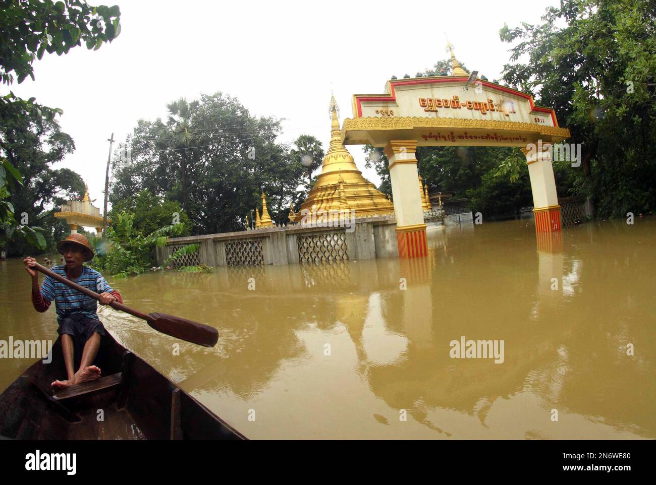 People paddle a boat through a flooded road after overflowing the Bago ...