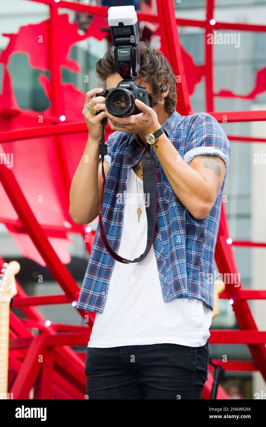 One Direction member Harry Styles takes photos of fans before ...