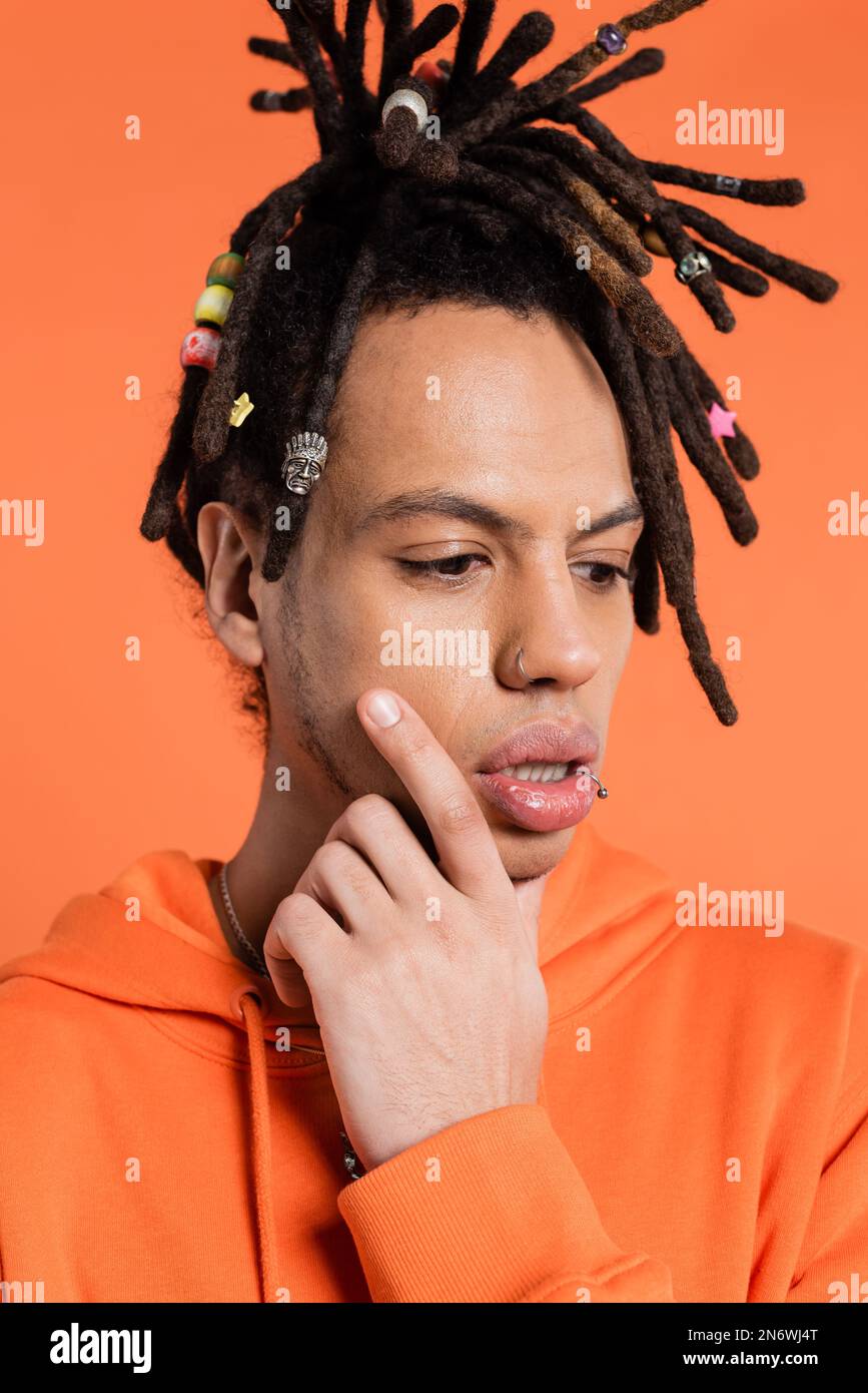 portrait of multiracial man with dreadlocks touching face while ...