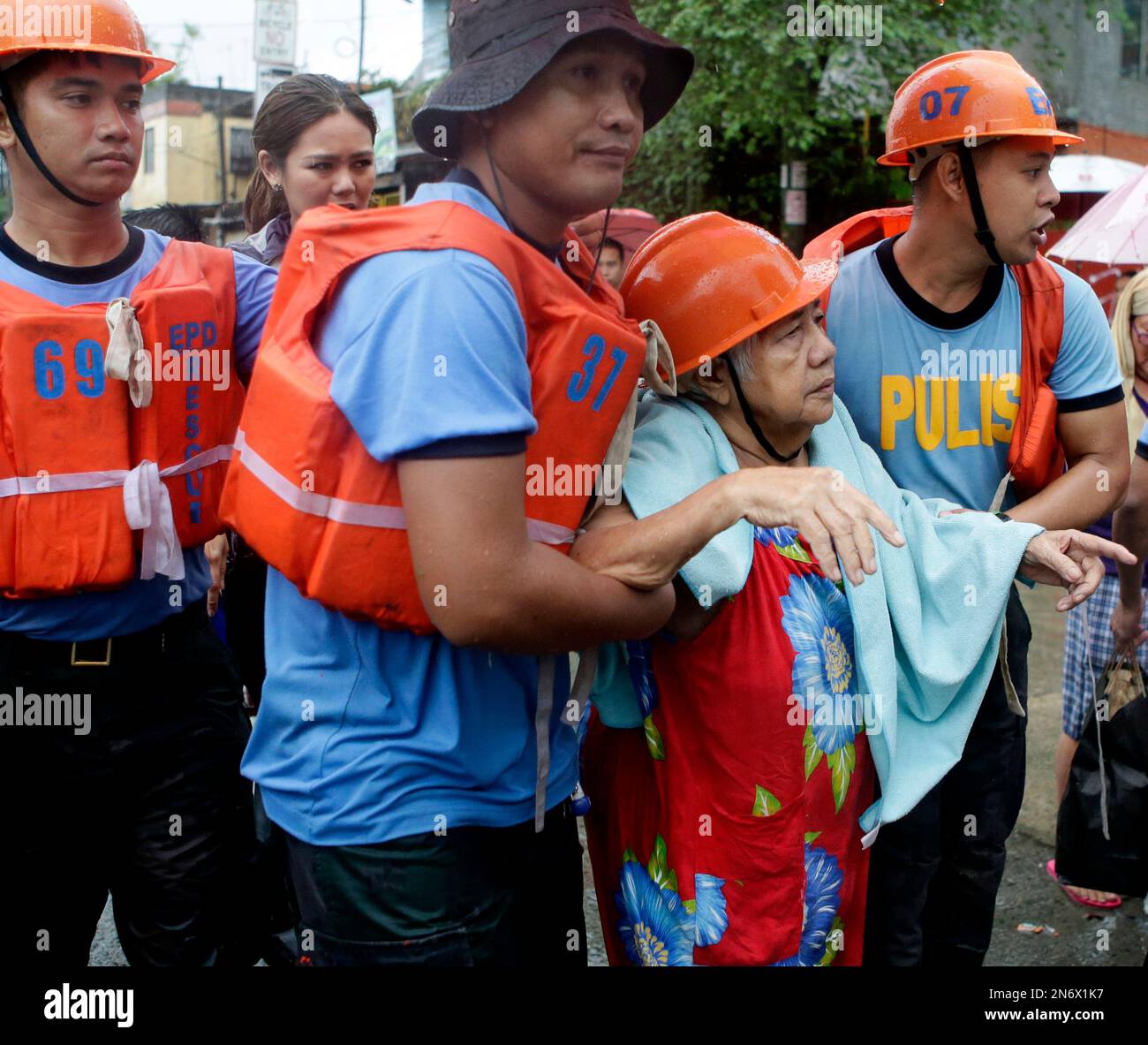 Philippine National Police officers help a resident to a waiting police ...