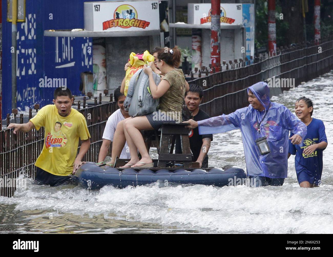 Commuters react to the waves created by a passing passenger bus at ...