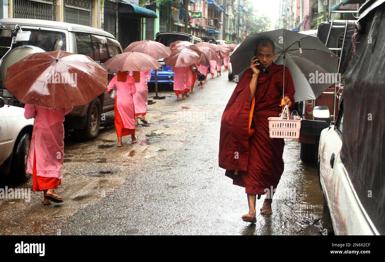 A Buddhist monk talks on his mobile phone as a group of nuns walk in ...