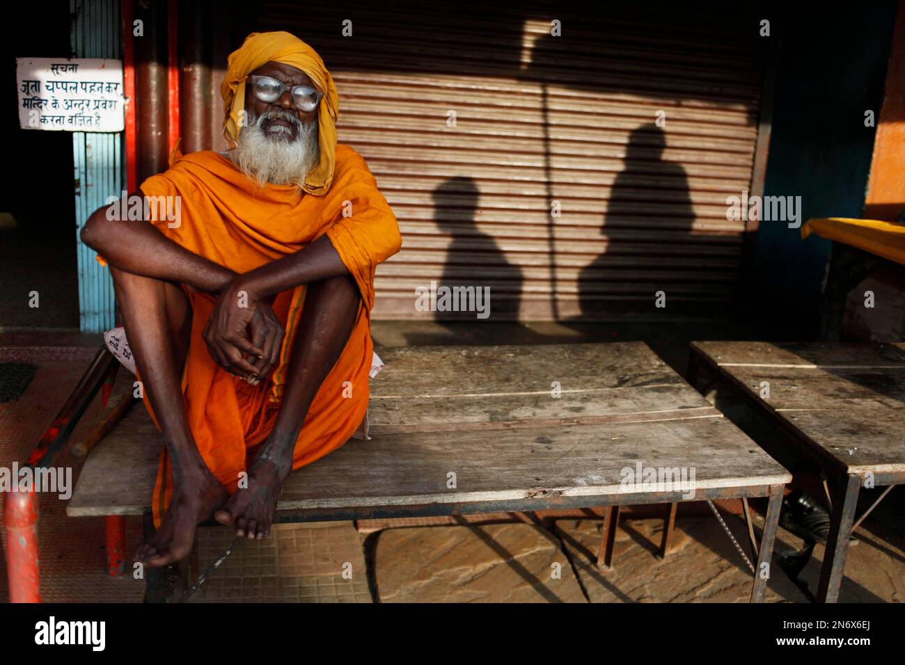 A Sadhu, or a Hindu holy man, sits on a table outside the temple of ...