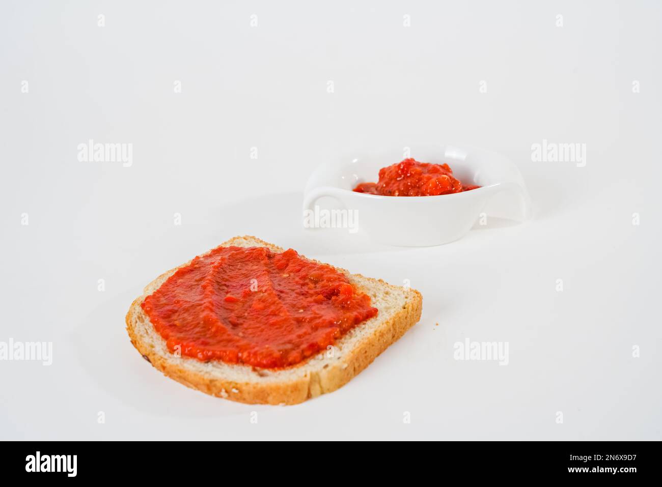 Chili tomato sauce with a slice of bread and small sauce cup isolated ...