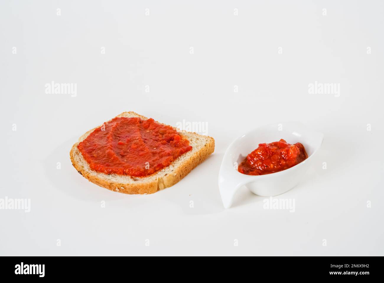 Chili tomato sauce with a slice of bread and small sauce cup isolated ...