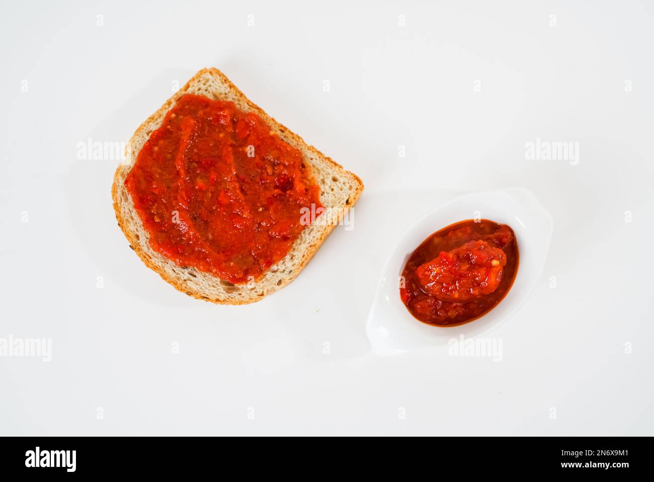 Chili tomato sauce with a slice of bread and small sauce cup isolated ...