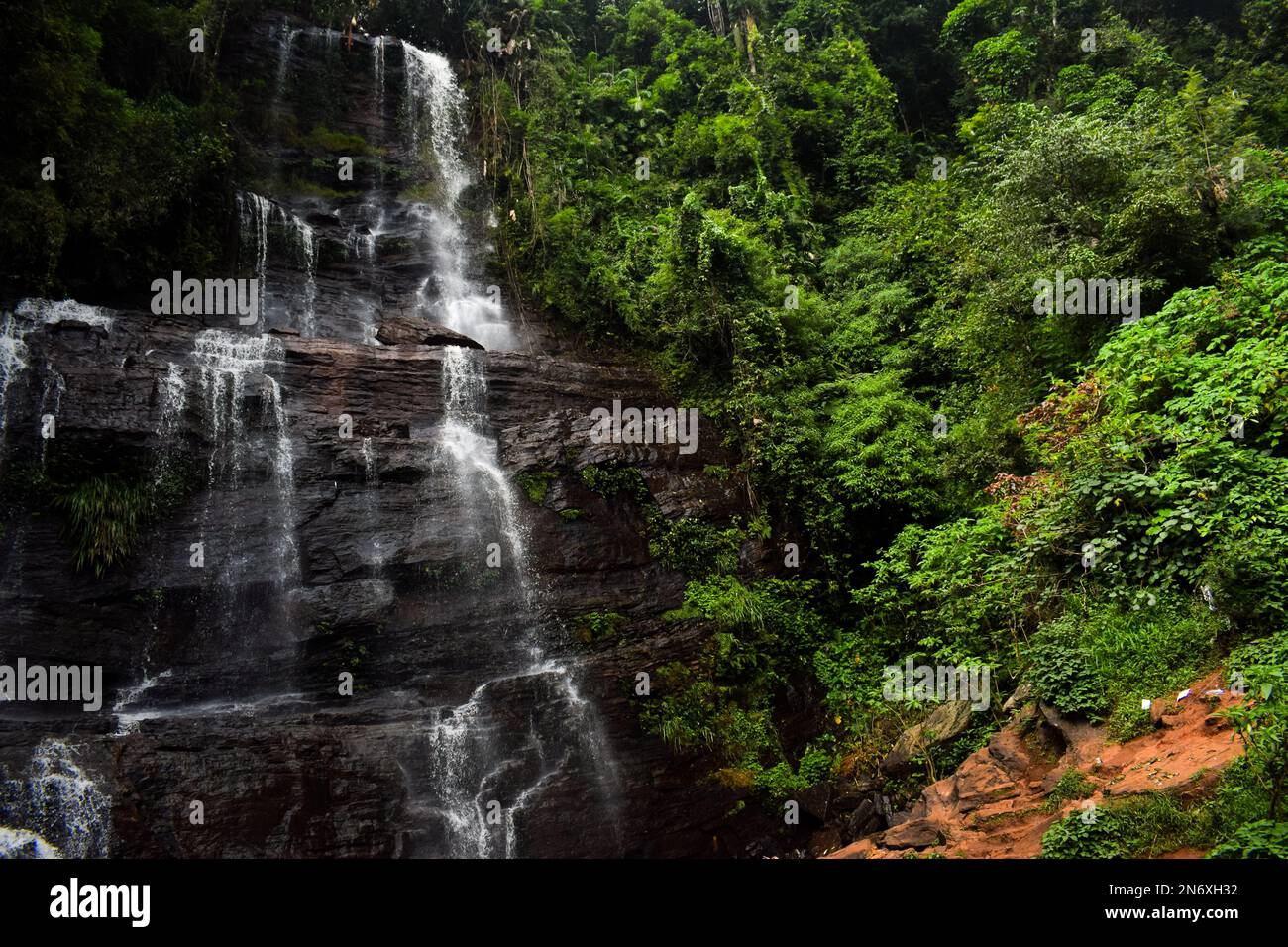A gorgeous view of a waterfall streaming down a steep cliff surrounded ...