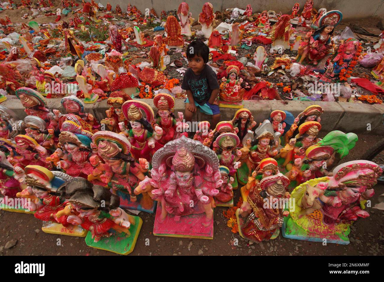 A young Indian child sits amidst the idols of Hindu goddess Dashama in ...