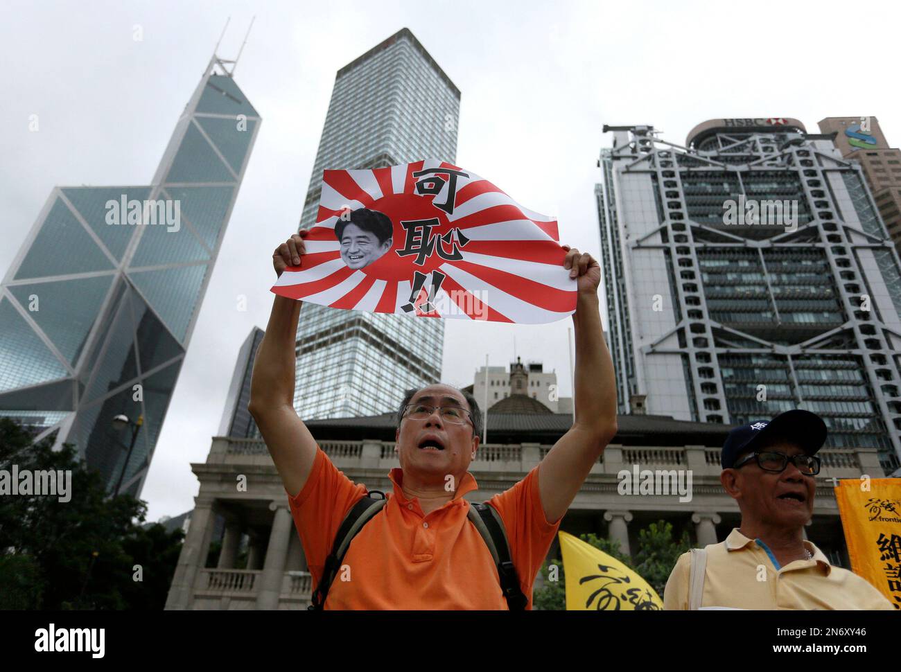 An anti-Japan protester demonstrates with a Japanese military flag ...