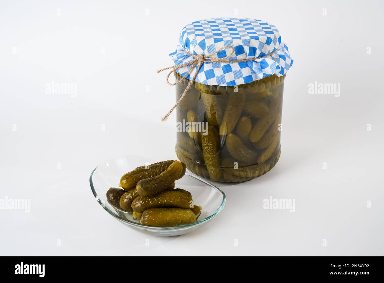 Pickled gherkins in jar and glass plate isolated on white background ...