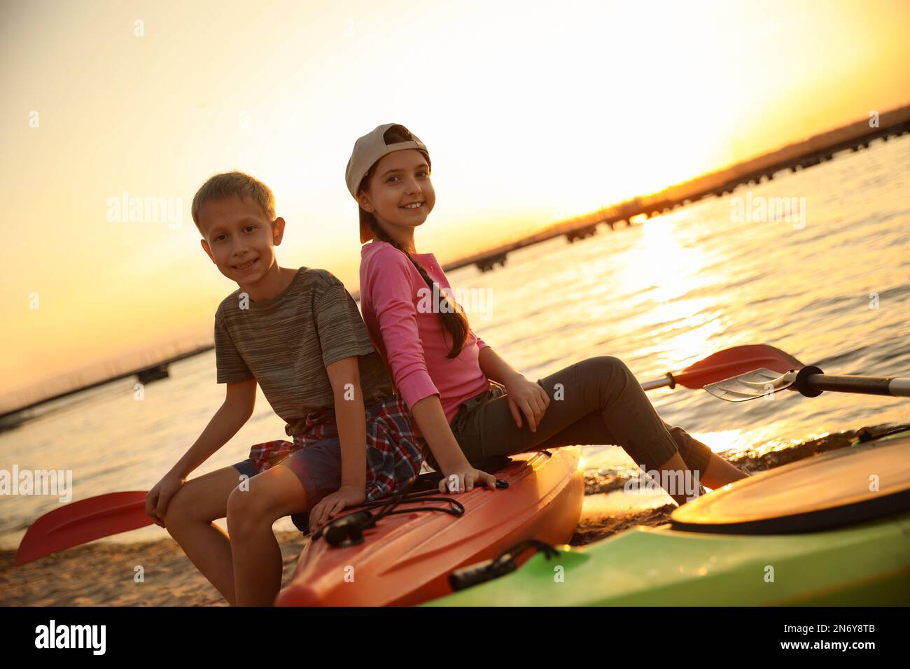 Happy children sitting on kayak near river at sunset. Summer camp Stock ...
