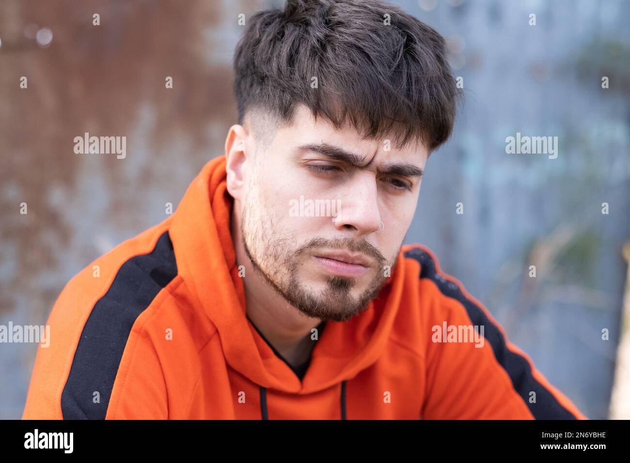 A young Caucasian man sitting with a worrisome face Stock Photo - Alamy