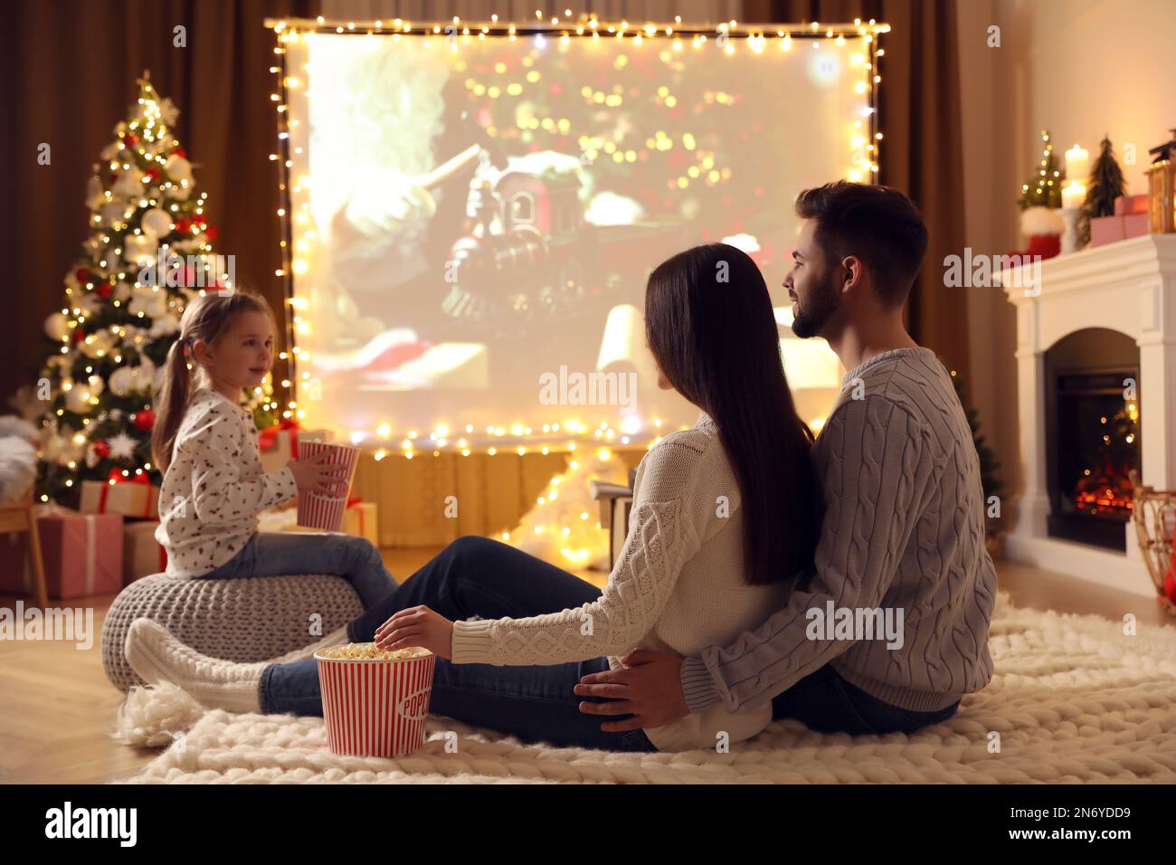 Family watching movie on projection screen in room decorated for ...