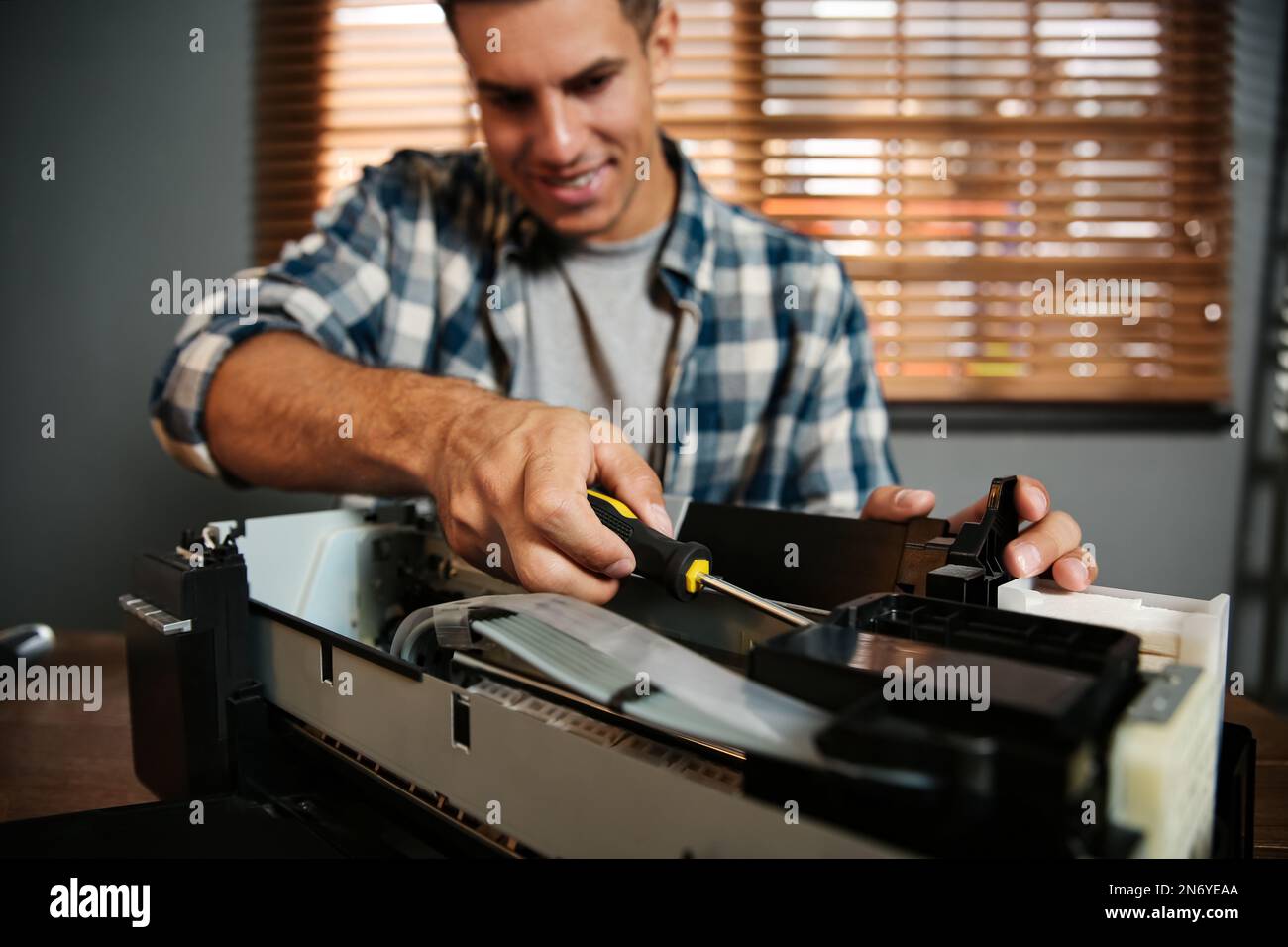 Repairman with screwdriver fixing modern printer in office, focus on ...