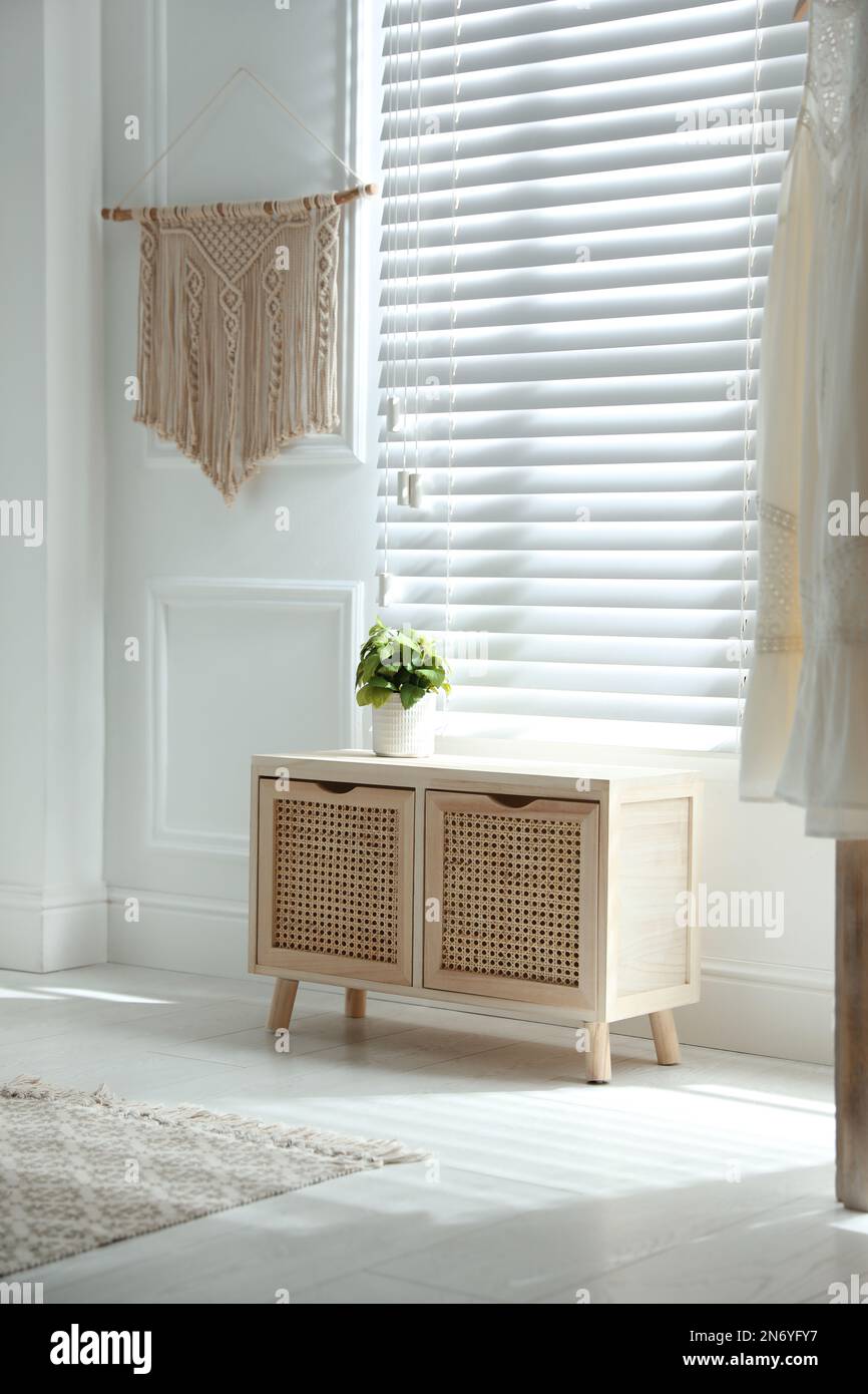 Wooden commode near window in room. Interior design Stock Photo - Alamy