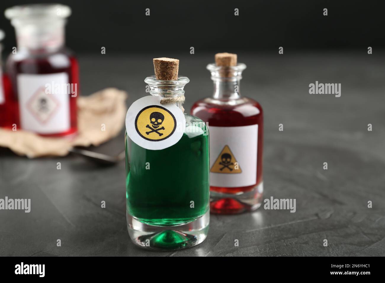 Glass bottles of poisons with warning signs on grey stone table Stock ...