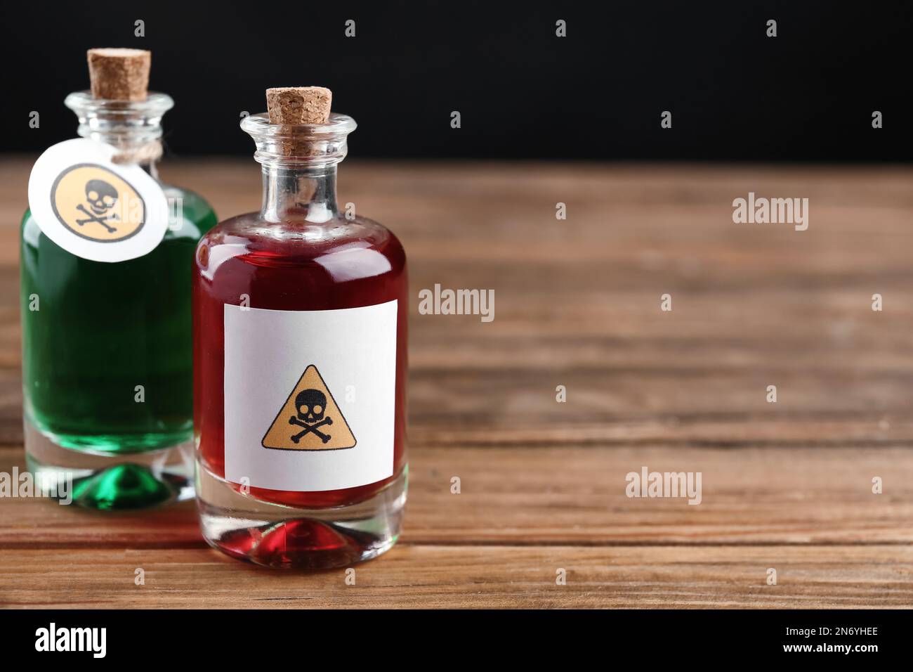 Glass bottles of poisons with warning signs on wooden table, closeup ...
