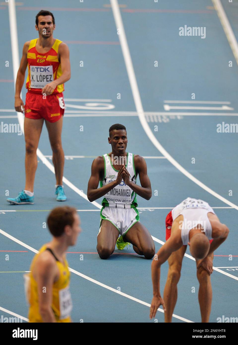 Saudi Arabia's Abdulaziz Ladan Mohammed, center, crouches on the track after competing in a men ...