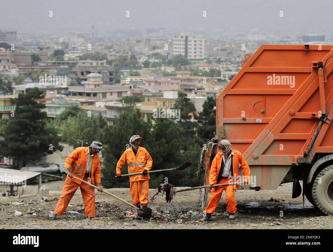 Afghan municipal workers clean up garbage on a street in Kabul ...