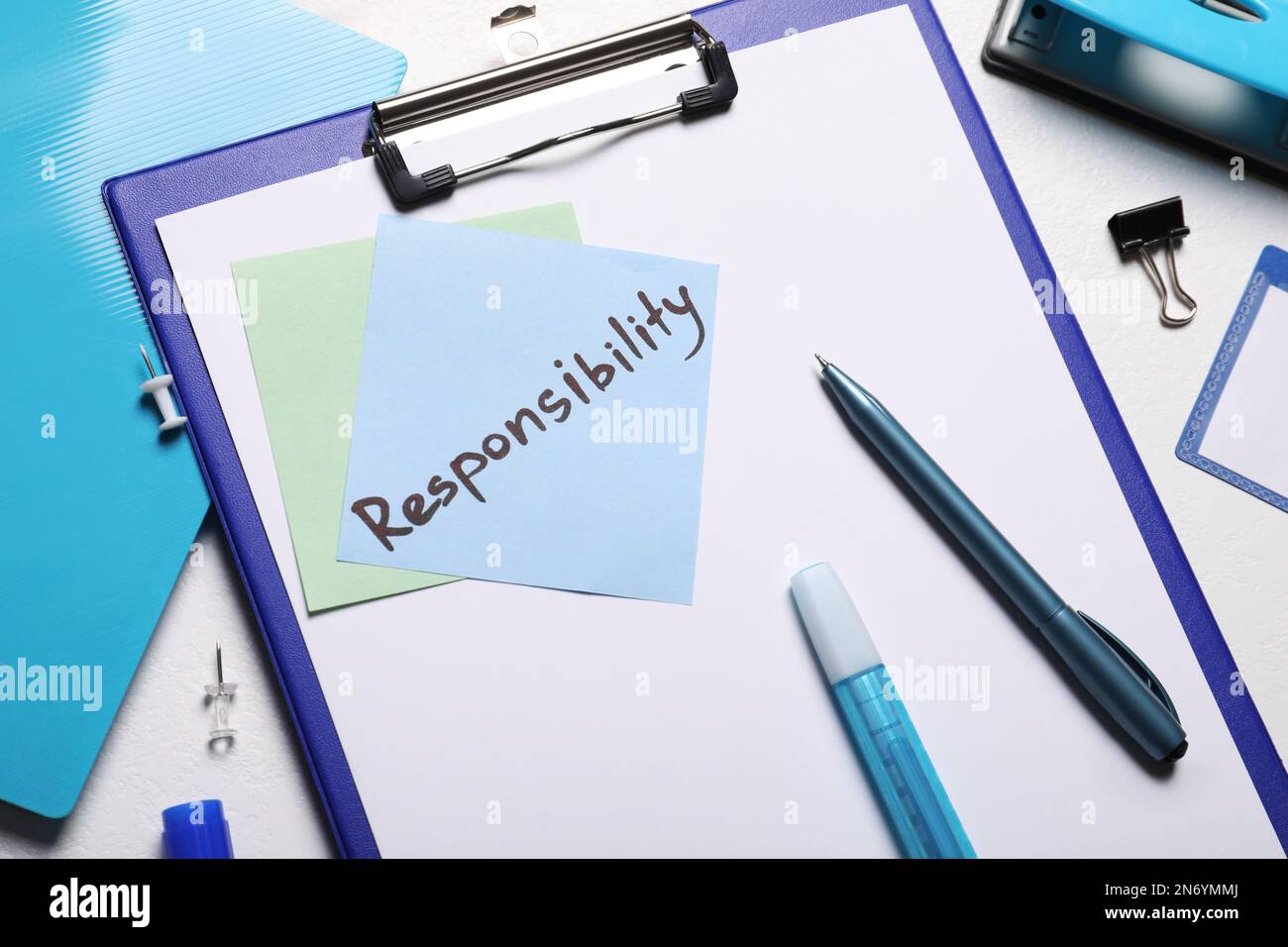 Blue note with word Responsibility among office supplies on white table ...