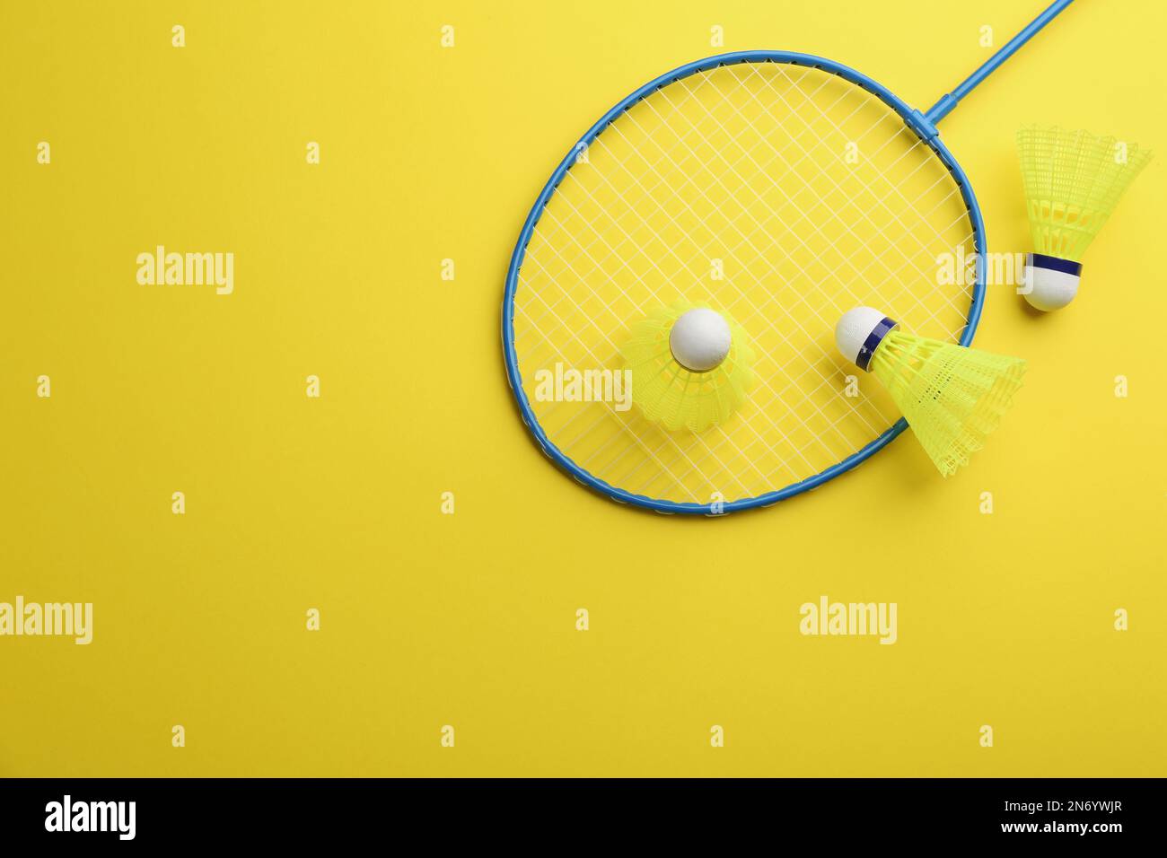 Badminton racket and shuttlecocks on yellow background, flat lay. Space ...