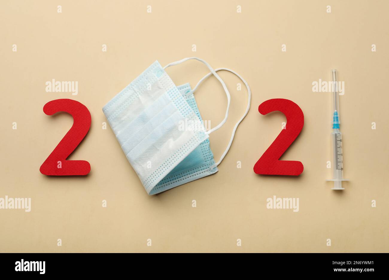 Paper numbers, medical mask and syringe forming 2021 on beige ...