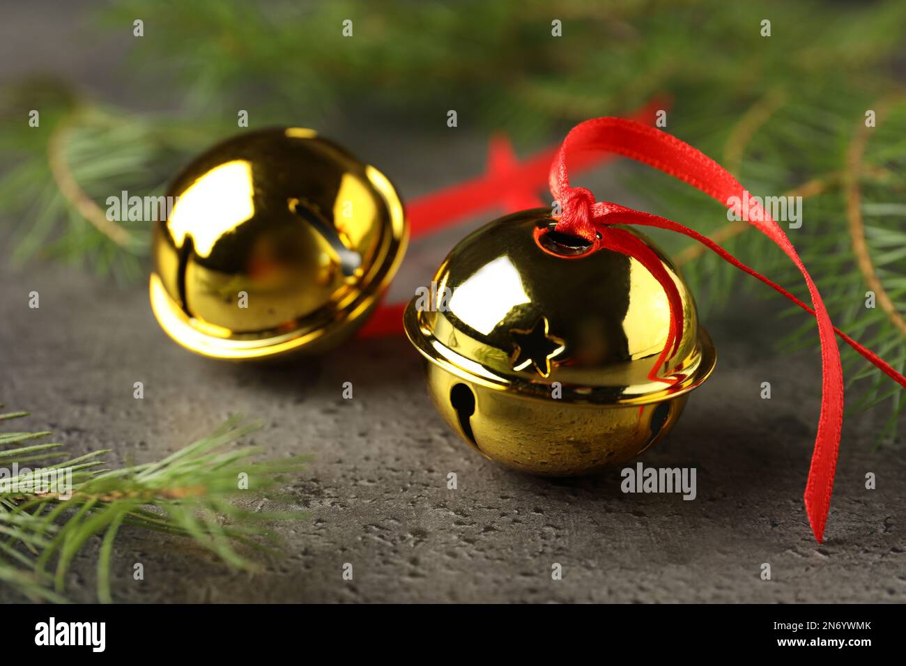 Golden sleigh bells and fir branches on grey background, closeup Stock ...