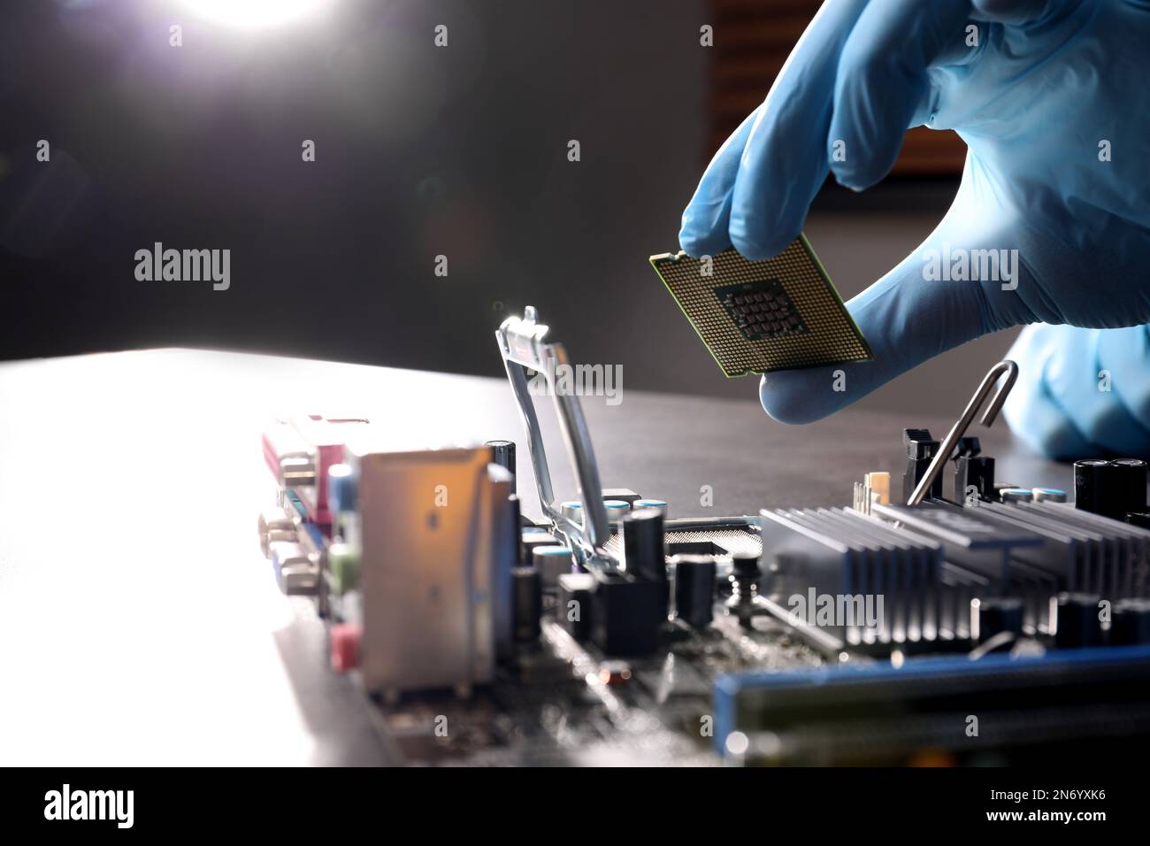 Technician repairing computer motherboard at table, closeup. Electronic ...