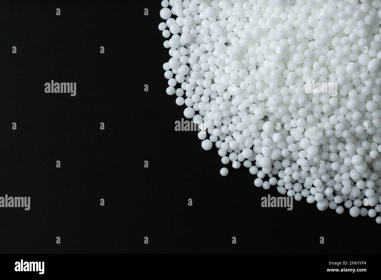 Pellets of ammonium nitrate on black background, flat lay with space ...