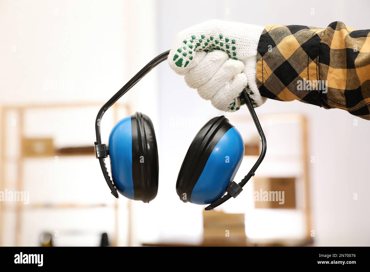 Worker holding safety headphones indoors, closeup. Hearing protection ...
