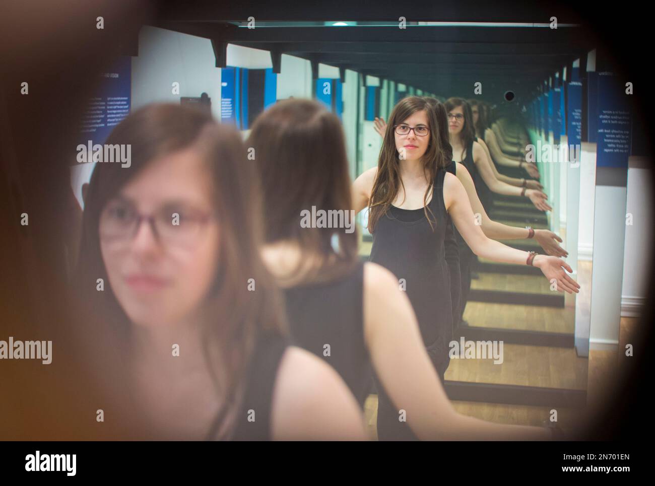 A woman is seen through a hole as she stands between two mirrors ...