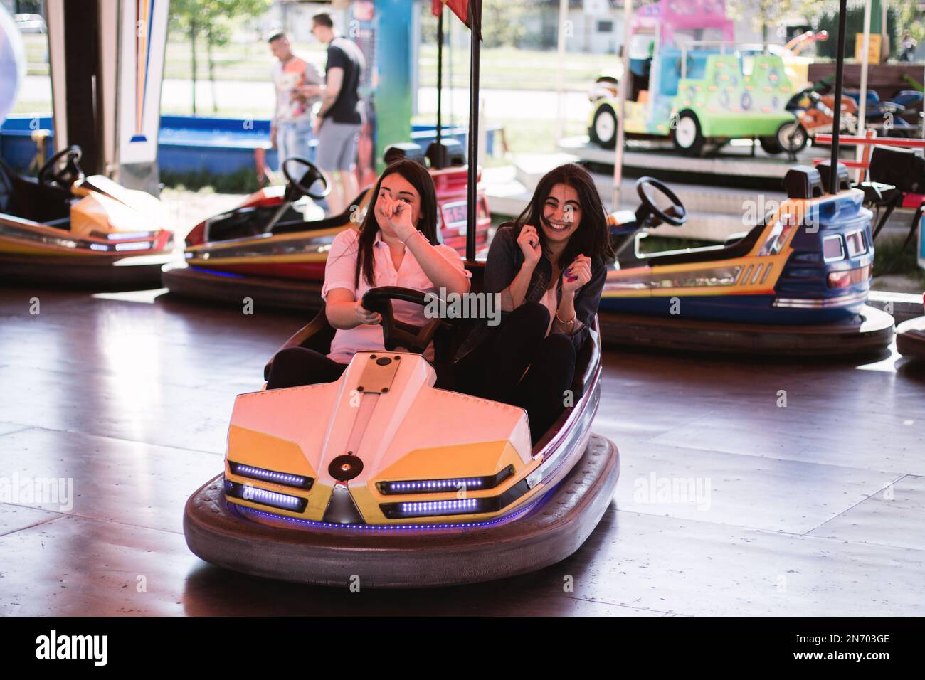 Two young women having a fun bumper car ride at the amusement park ...