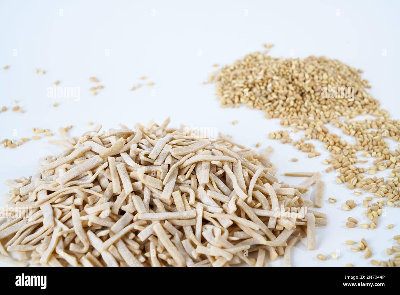 Uncooked homemade egg noodles and coarse bulgur wheat grains isolated ...