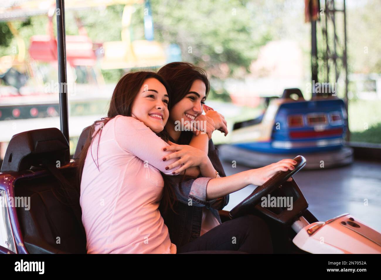 Two young women having a fun bumper car ride at the amusement park ...