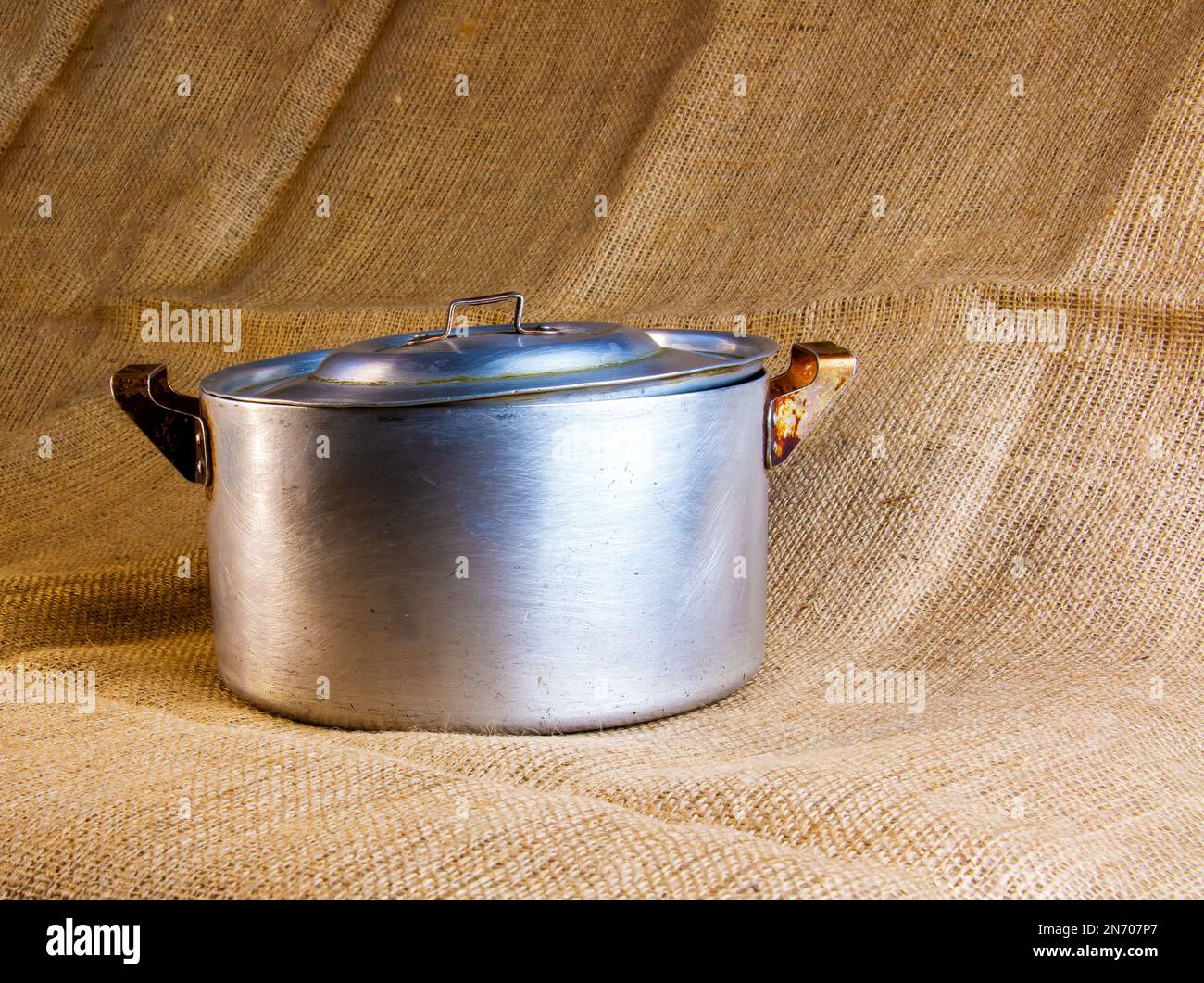 An old aluminum pan made in circa 1960 against a background of burlap ...