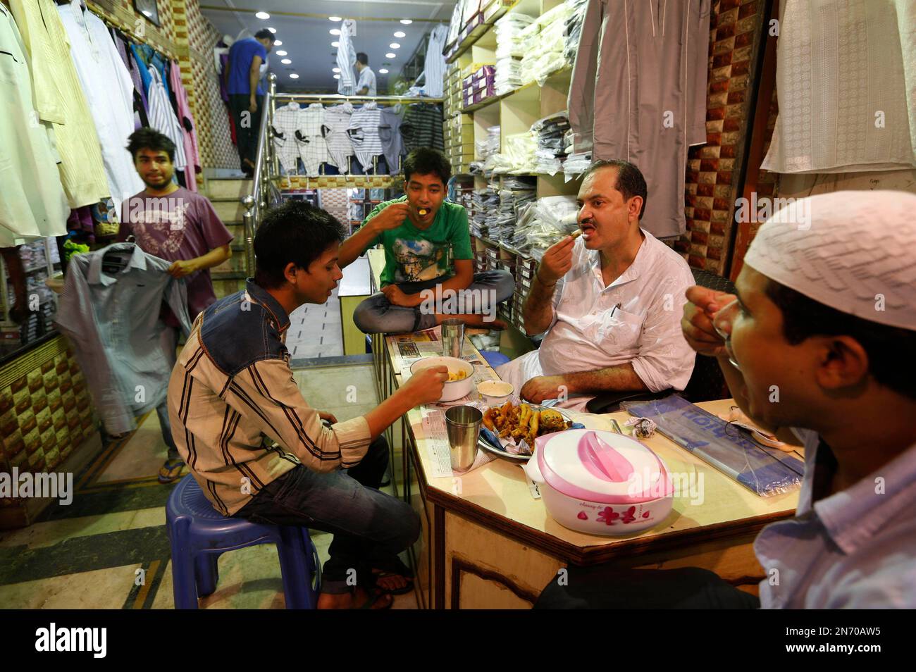 A devout Muslim shop owner and his helpers break their fast as evening ...