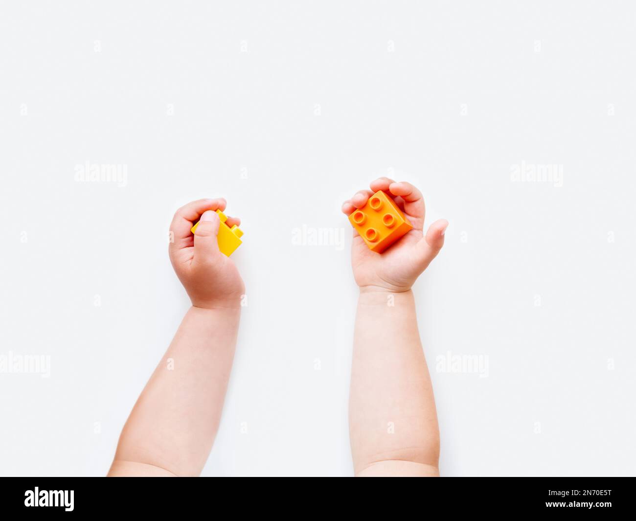 Child is holidng orange and blue constructor blocks in fist. Kid's ...