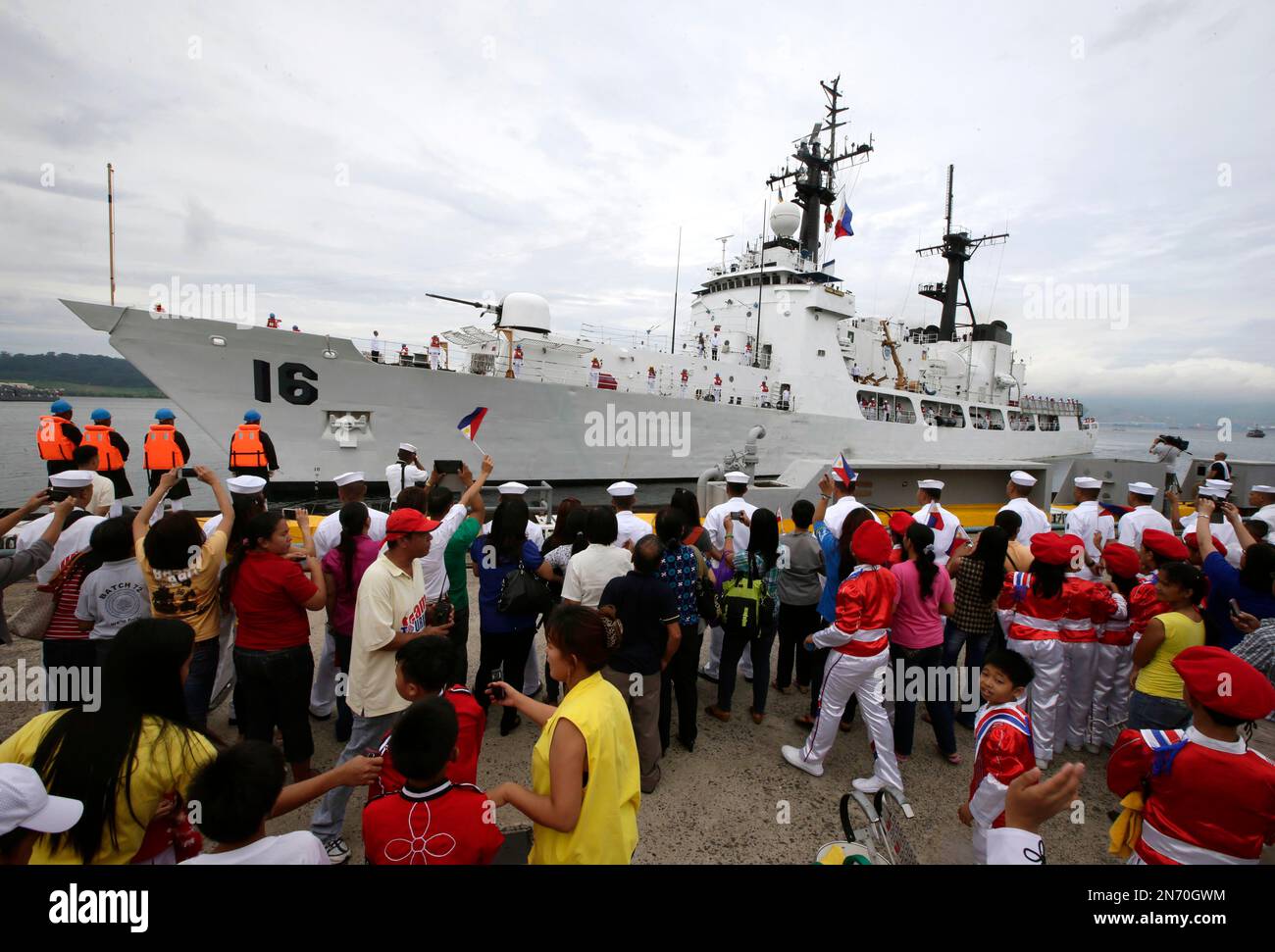 Students and other guests wave Philippine flags to welcome the second ...