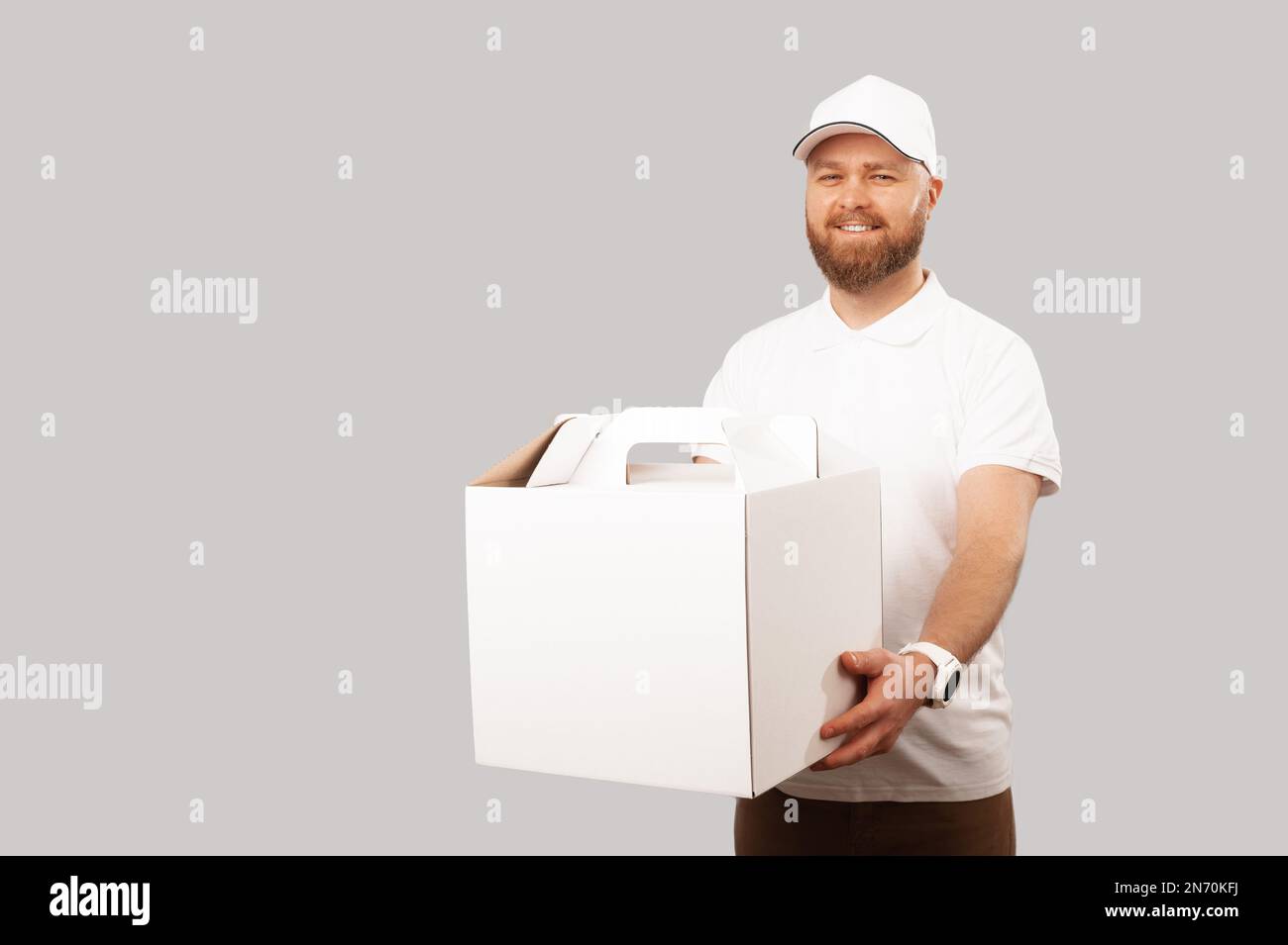 Strong smiling delivery man wearing white carries a cake delivery box ...