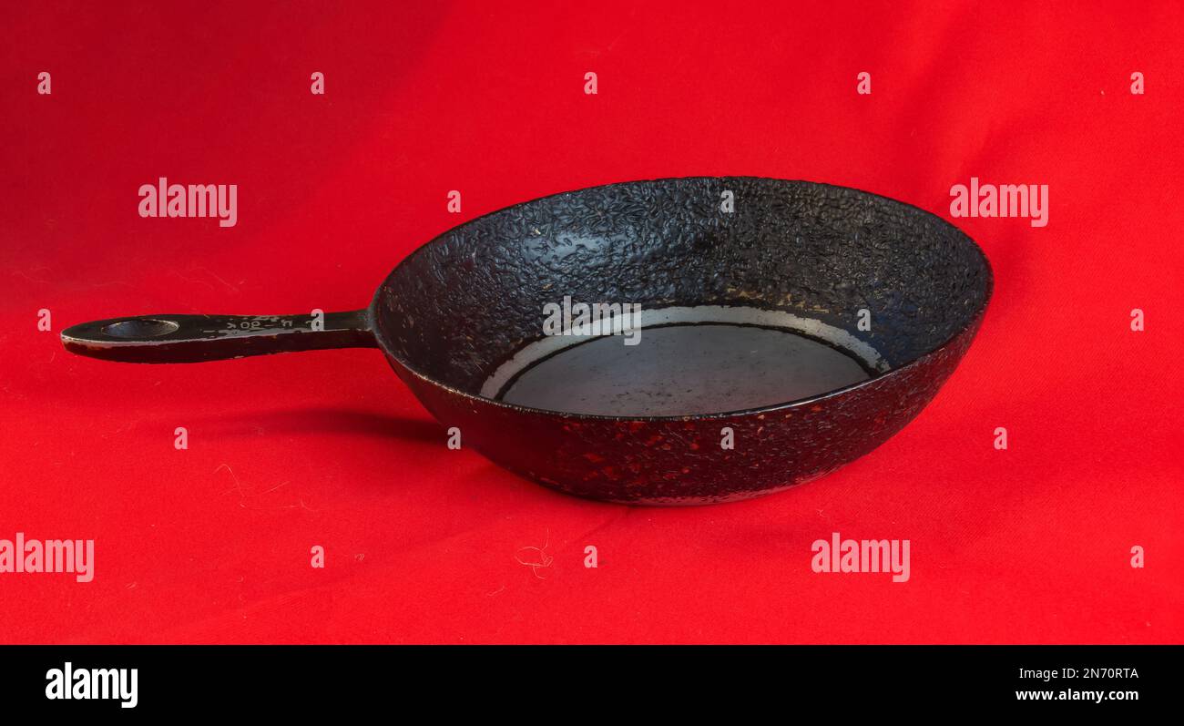 An old cast iron skillet made in circa 1960 against a red background ...