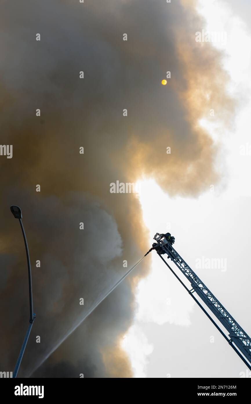A vertical low-angle of the firefighters blowing the massive fire smoke ...