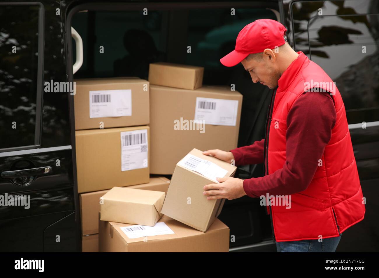 Courier with parcels near delivery van outdoors Stock Photo - Alamy
