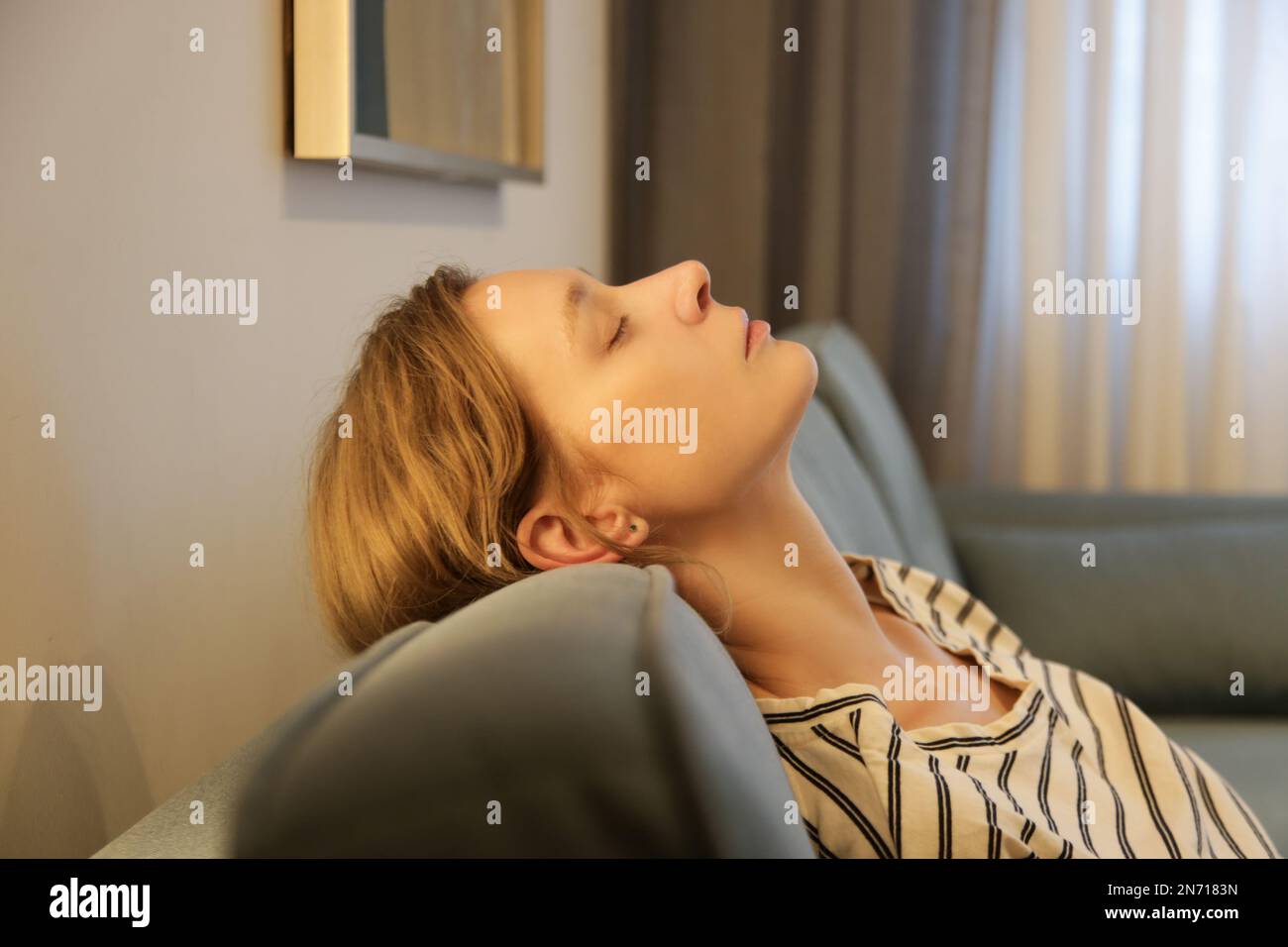 Side view of young pretty woman relaxing on sofa, woman leaning her ...