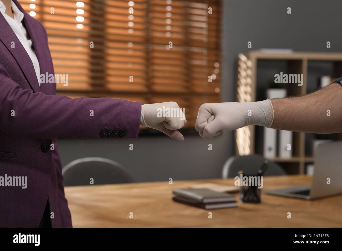 Office employees greeting each other by bumping fists at workplace ...