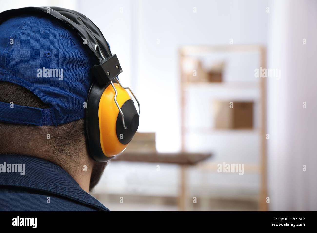 Worker wearing safety headphones indoors, closeup. Hearing protection ...