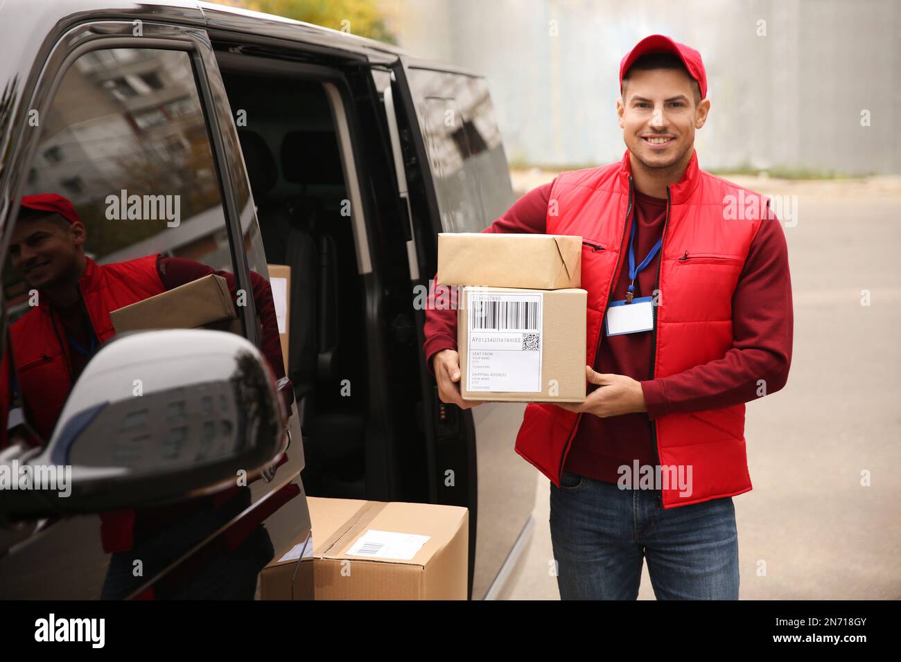 Courier with parcels near delivery van outdoors Stock Photo - Alamy