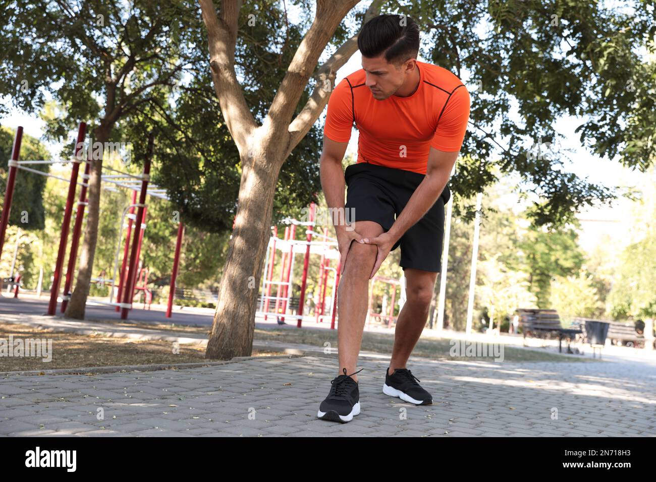 Man in sportswear having knee problems on sports ground Stock Photo - Alamy
