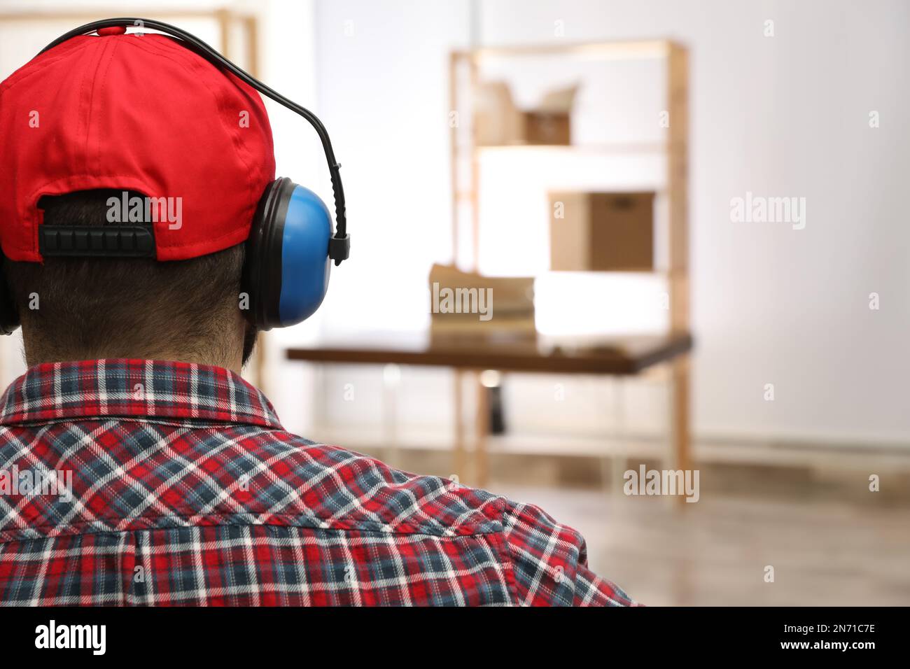 Worker wearing safety headphones indoors, back view. Hearing protection ...
