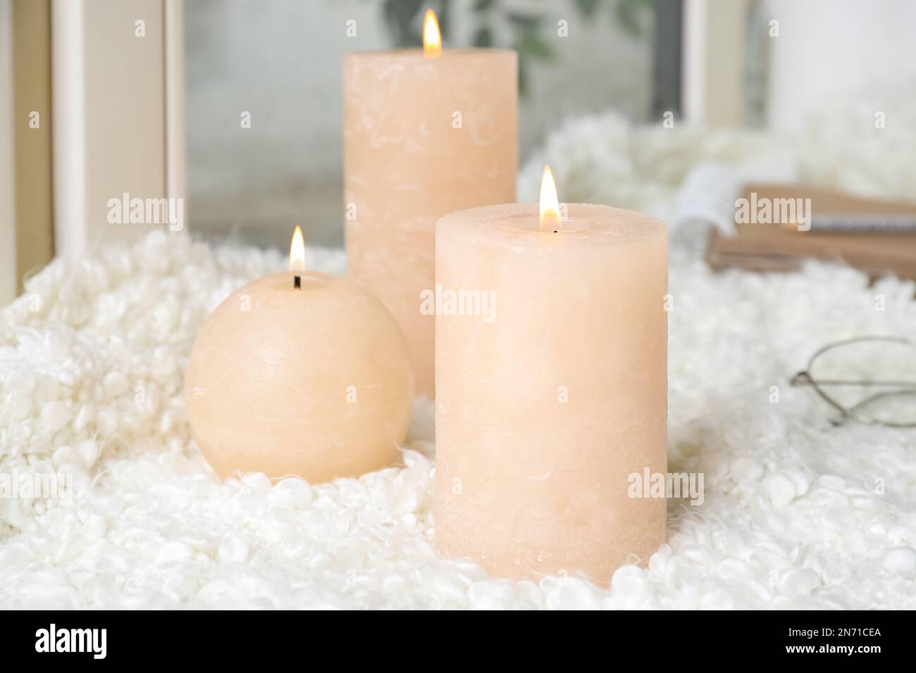 Burning wax candles on soft fabric indoors Stock Photo - Alamy