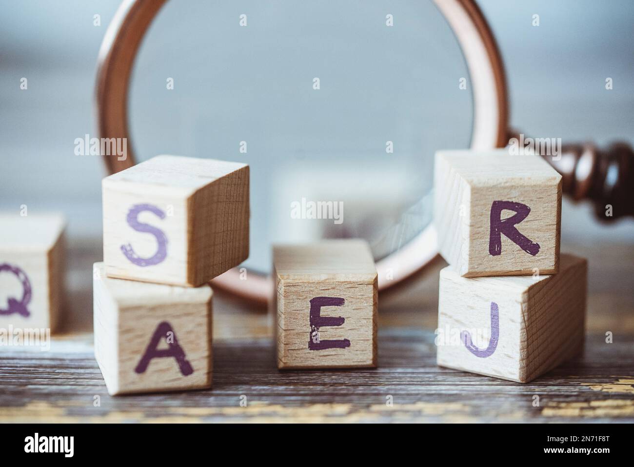 Close-up of a magnifying glass and wooden blocks with capital letters ...